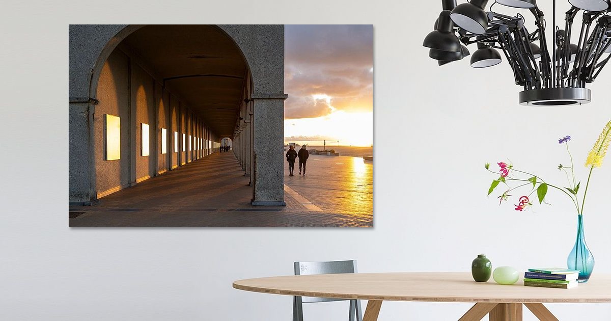 De lage winterzon komt onder de wolken vandaan en werpt een gouden licht over de boulevard en ...